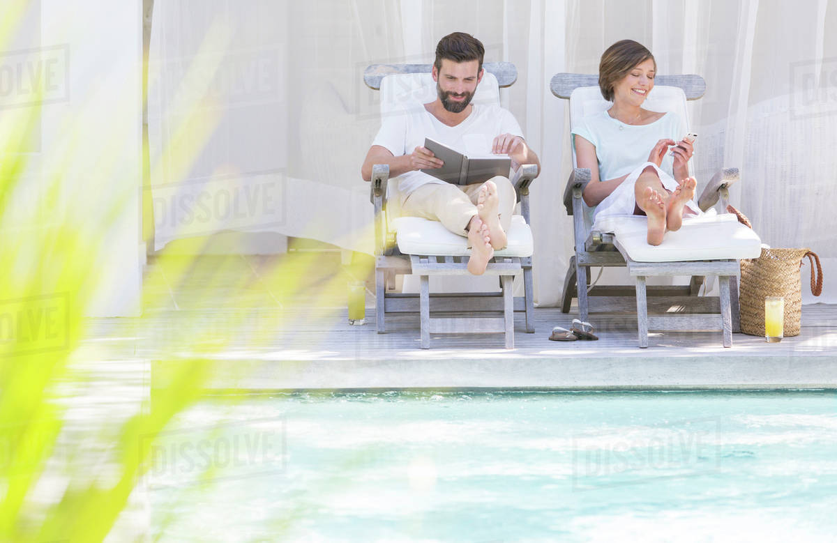 Couple relaxing in lawn chairs by swimming pool - Royalty-free Stock ...