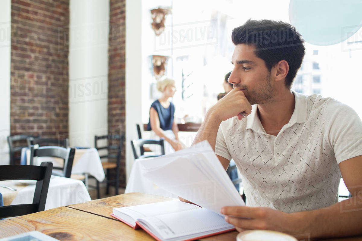 Businessman looking at documents in cafe - Stock Photo - Dissolve