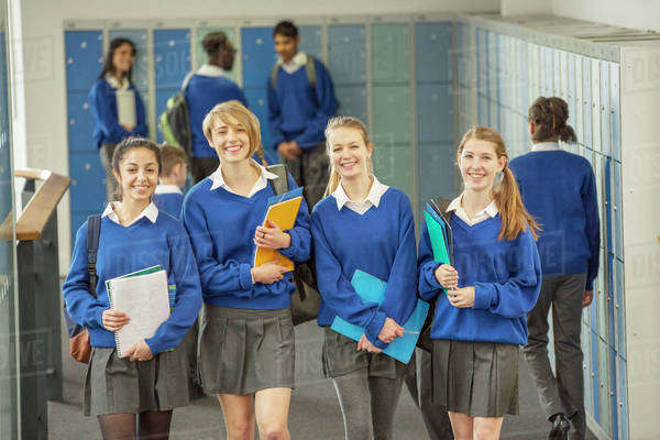 Portrait of smiling female students wearing school uniforms walking ...