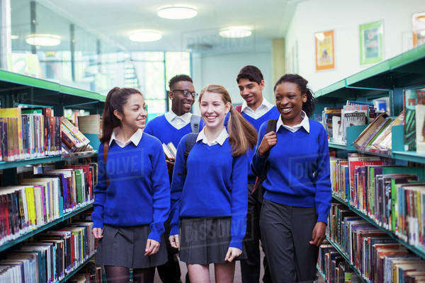 Smiling students wearing blue school uniforms walking between ...
