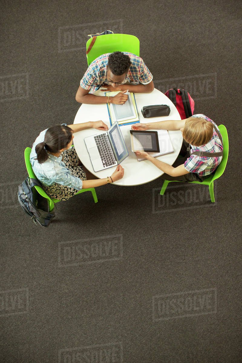 Overhead view of students doing homework together, using laptop and ...
