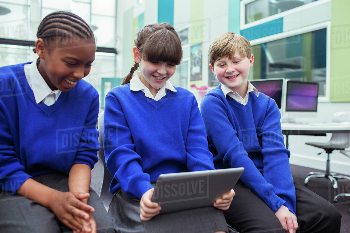 Primary school children wearing blue school uniforms holding digital ...