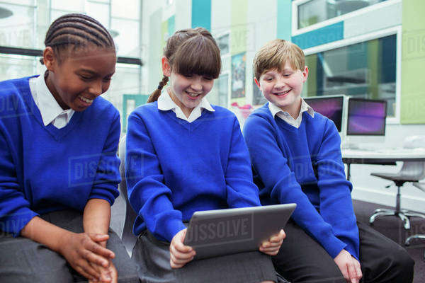 Primary school children wearing blue school uniforms holding digital ...