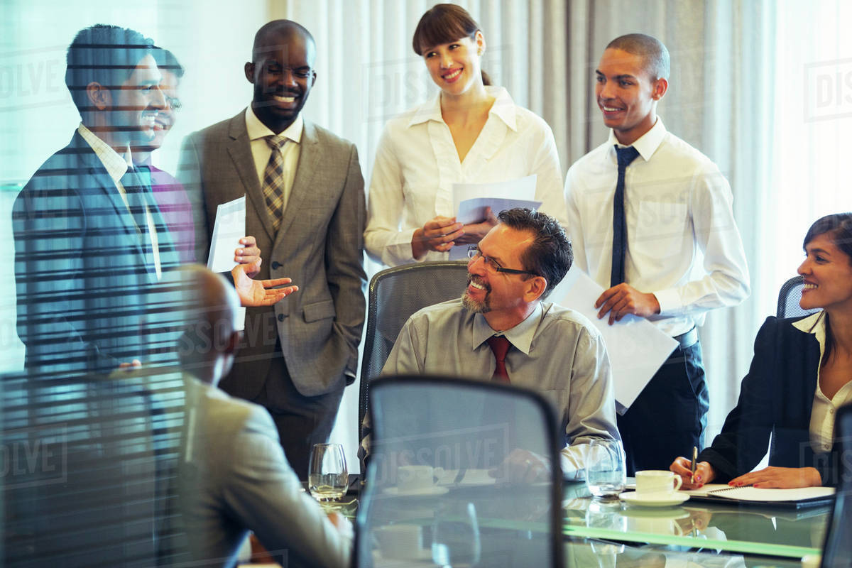 Business people smiling in conference room during business meeting ...