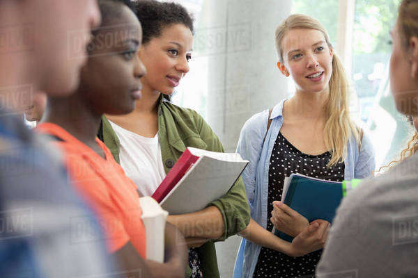 University students with books standing in corridor talking - Royalty ...