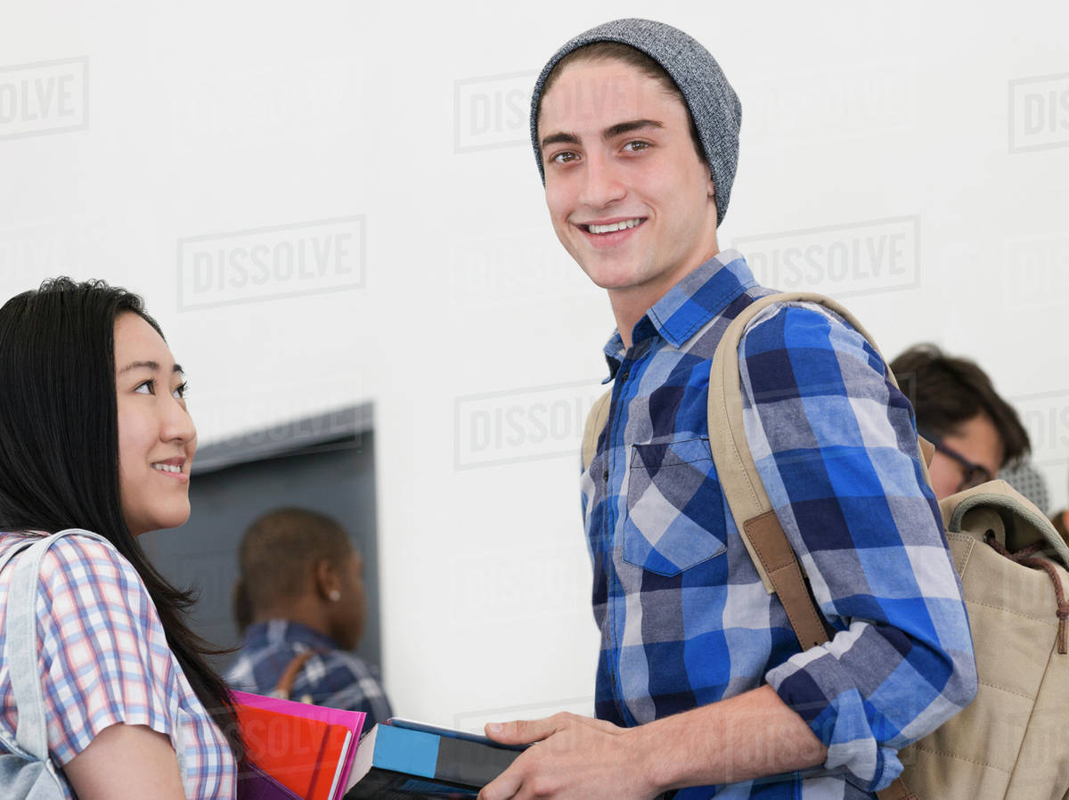 Portrait of university student with book standing in classroom ...