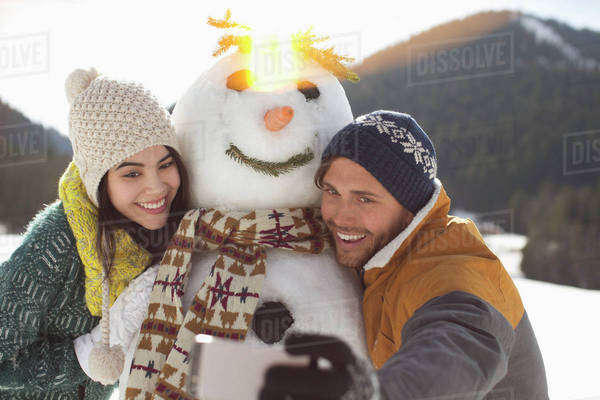 Couple taking selfie with snowman - Stock Photo - Dissolve