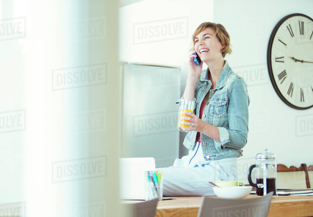 Young office worker sitting on desk at talking on phone - Royalty-free ...
