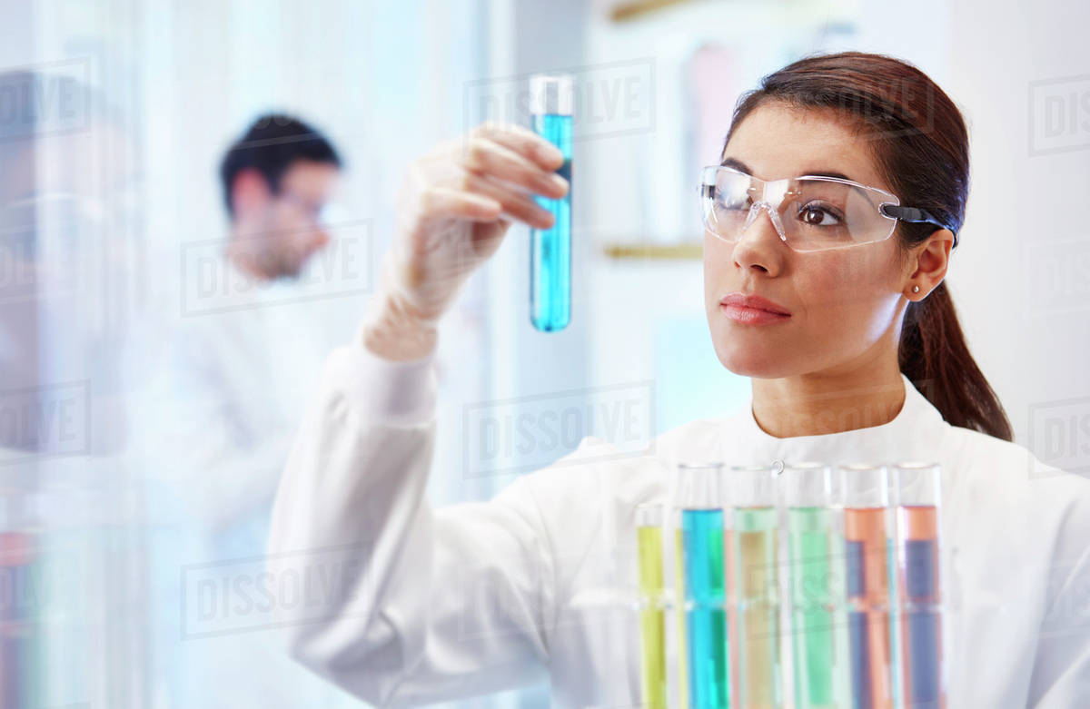 Woman in laboratory looking at vial with blue fluid - Royalty-free ...