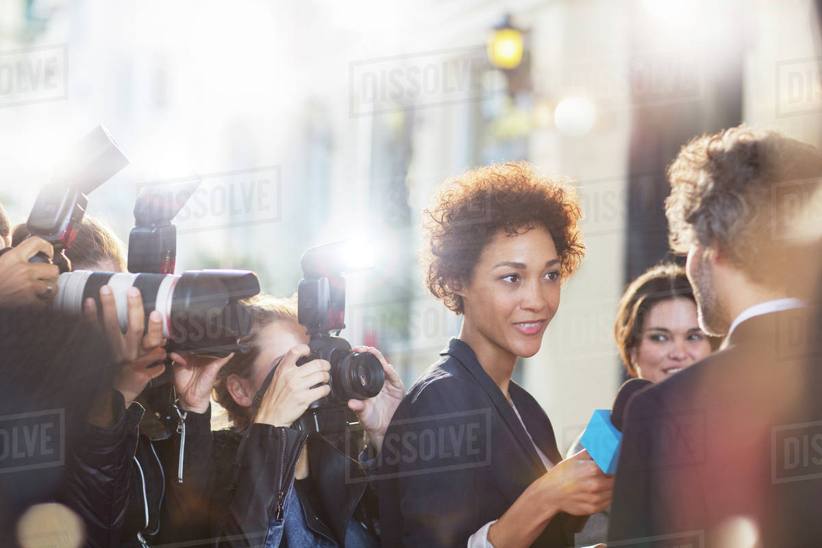 Celebrity being interviewed and photographed by paparazzi at event ...
