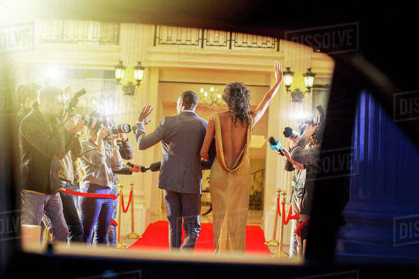 Celebrity couple arriving and waving to paparazzi photographers at red ...