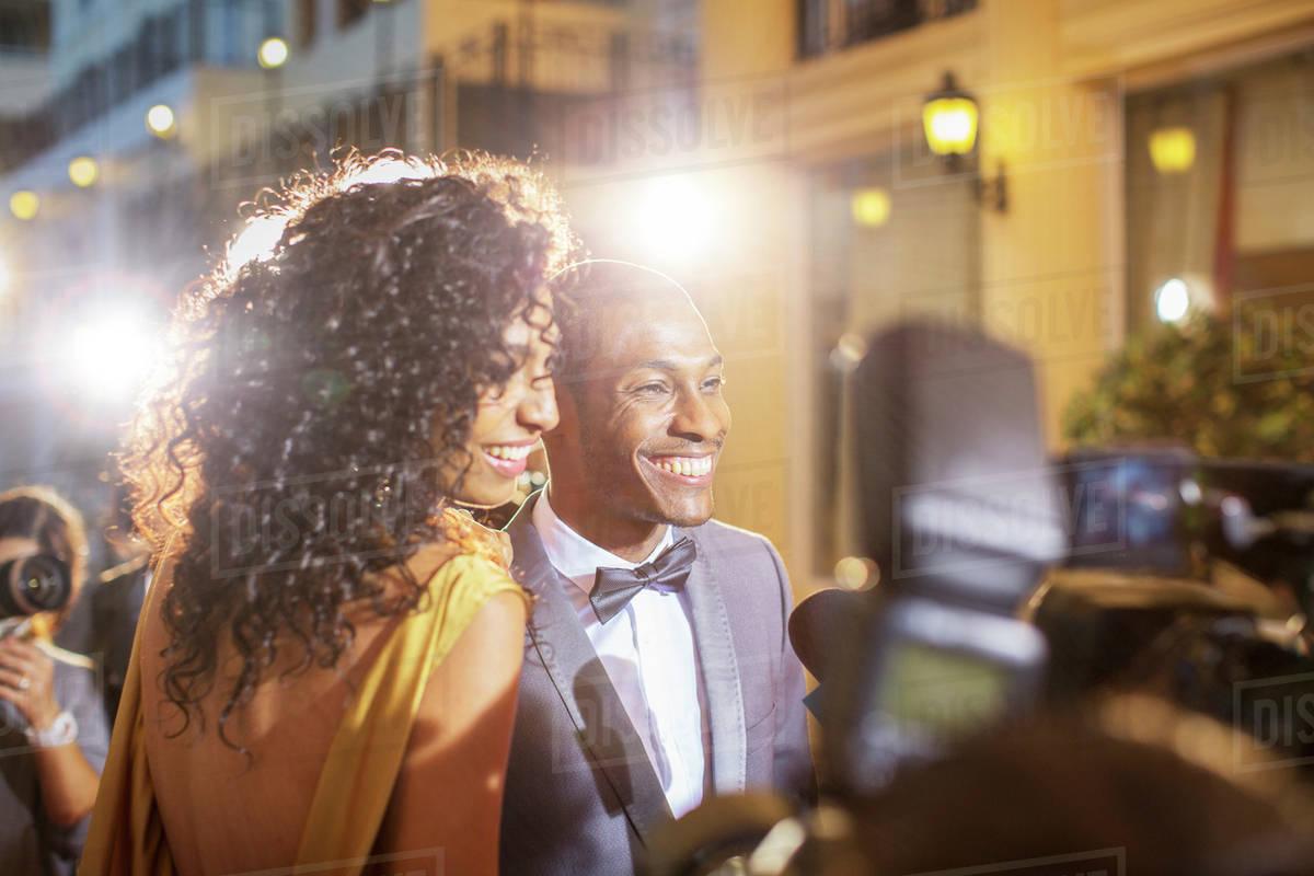 Smiling celebrity couple being interviewed and photographed by ...