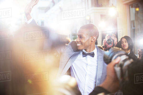 Smiling celebrity waving to paparazzi photographers at event - Stock ...