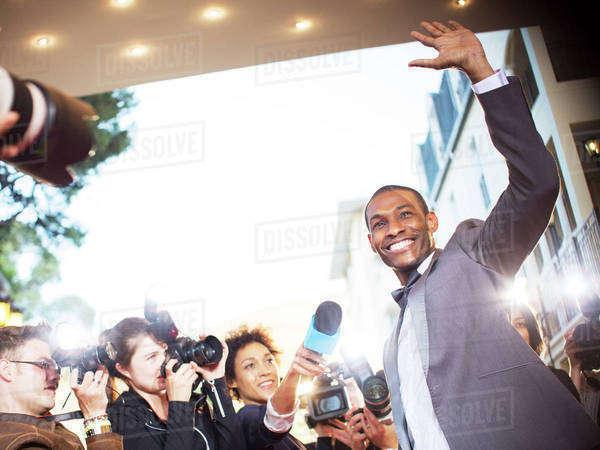 Waving celebrity being interviewed and photographed by paparazzi at ...