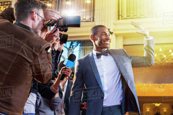 Celebrity waving and being photographed by paparazzi photographers ...