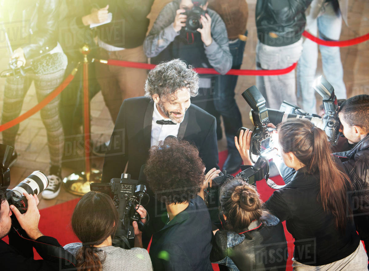 Celebrity being interviewed and photographed by paparazzi photographers ...