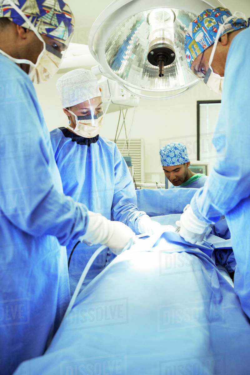 Surgeons performing surgery in operating room - Stock Photo - Dissolve
