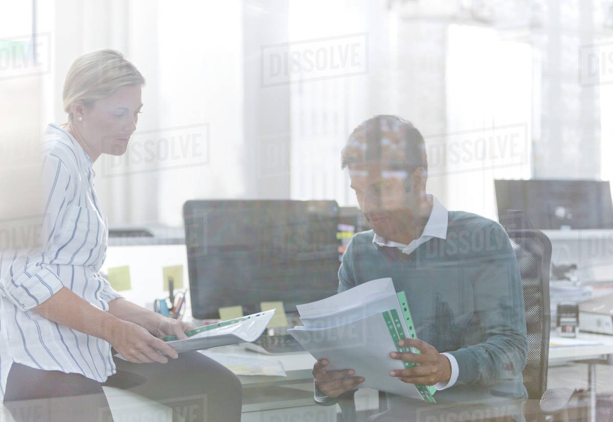 Business people reviewing paperwork at desk in office - Royalty-free ...