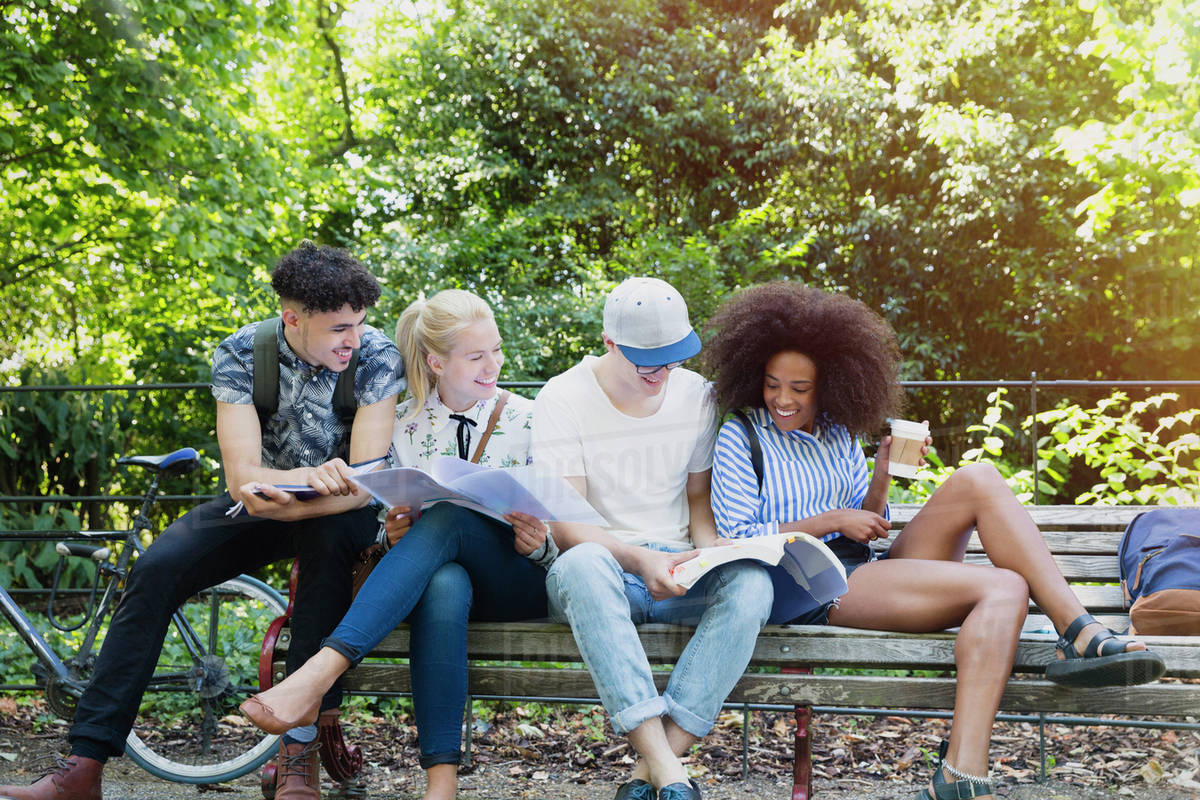 College students hanging out studying on park bench - Royalty-free ...