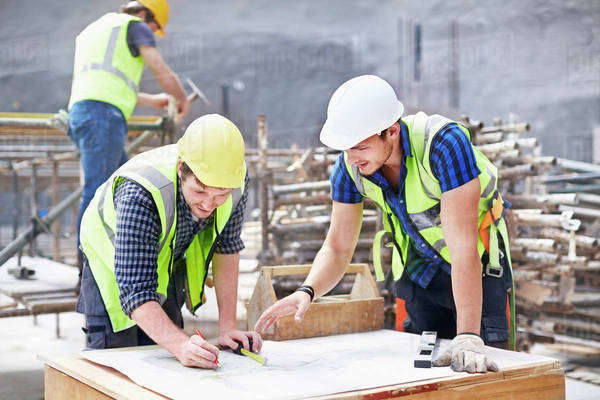 Construction worker and engineer revising blueprints at construction ...