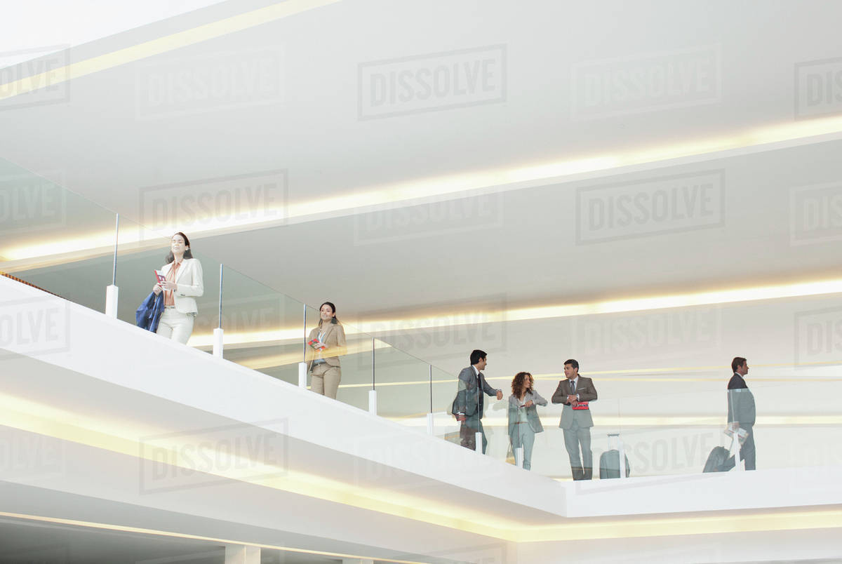 Business people leaning on glass railing of elevated walkway - Royalty ...
