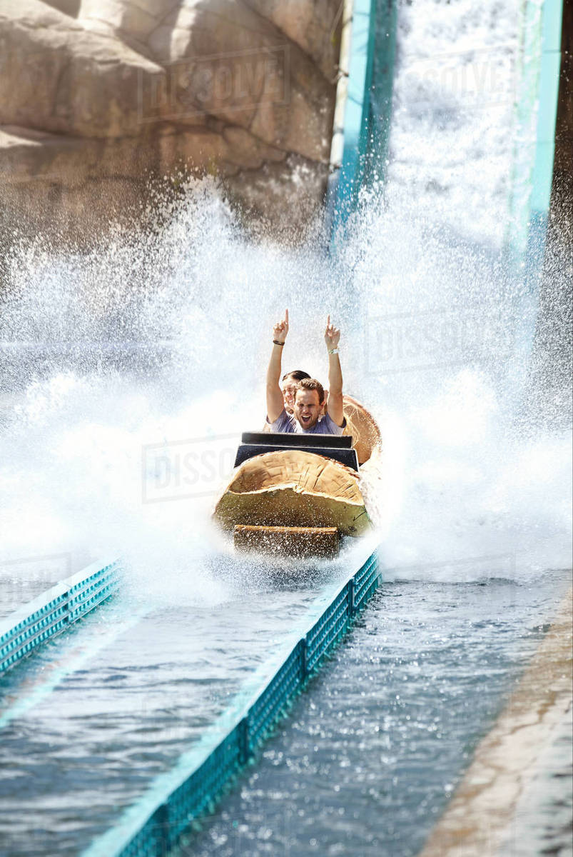 Enthusiastic young man riding water log amusement park ride - Royalty ...
