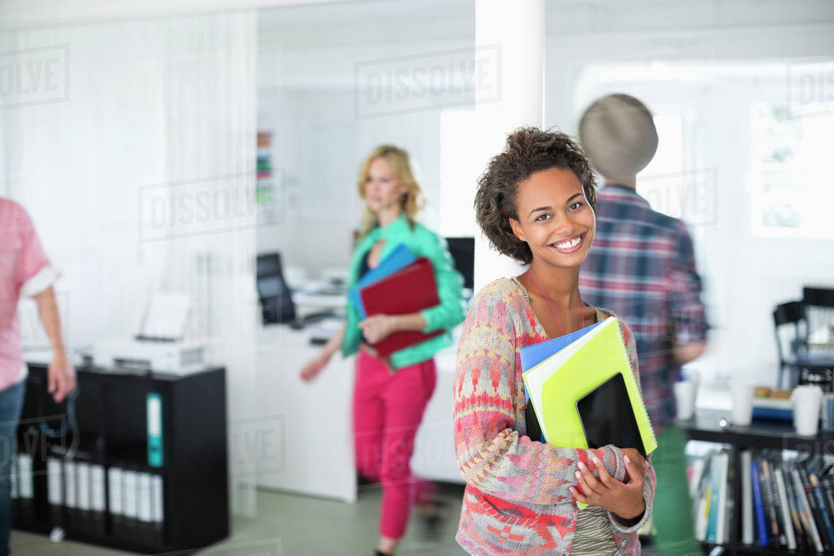 Businesswoman carrying folders in office - Stock Photo - Dissolve