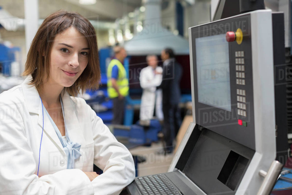 Portrait smiling female engineer at control panel in steel factory ...