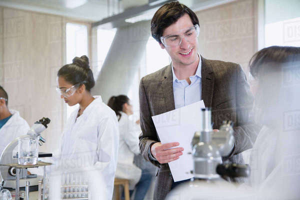 Science professor helping college student in science laboratory ...