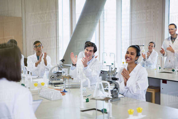 College students clapping for classmate in science laboratory classroom ...