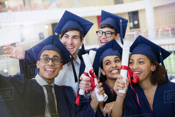 Happy college students in cap and gown holding diplomas posing for ...