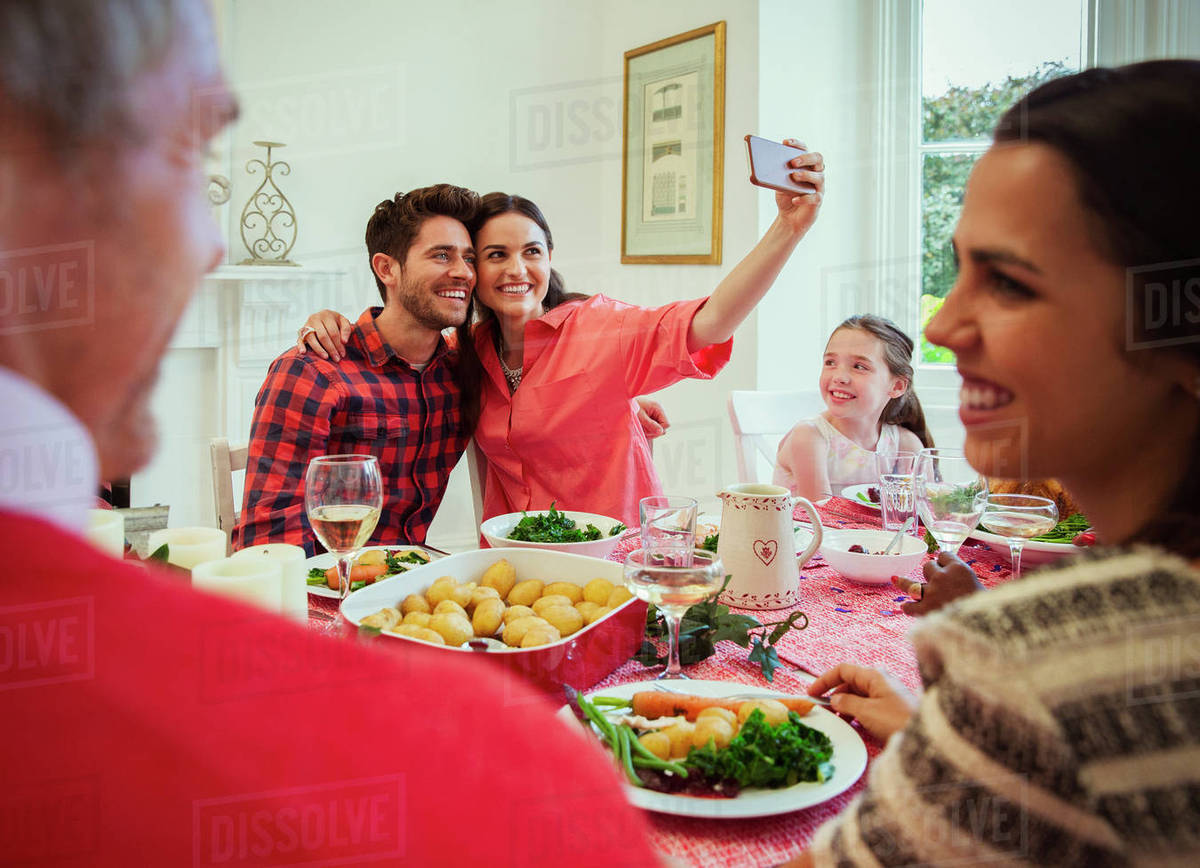 Couple with camera phone taking selfie at Christmas dinner table ...