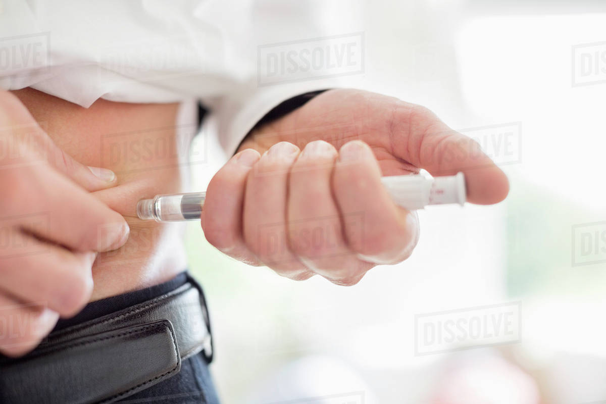 Man giving himself injection in stomach - Stock Photo - Dissolve