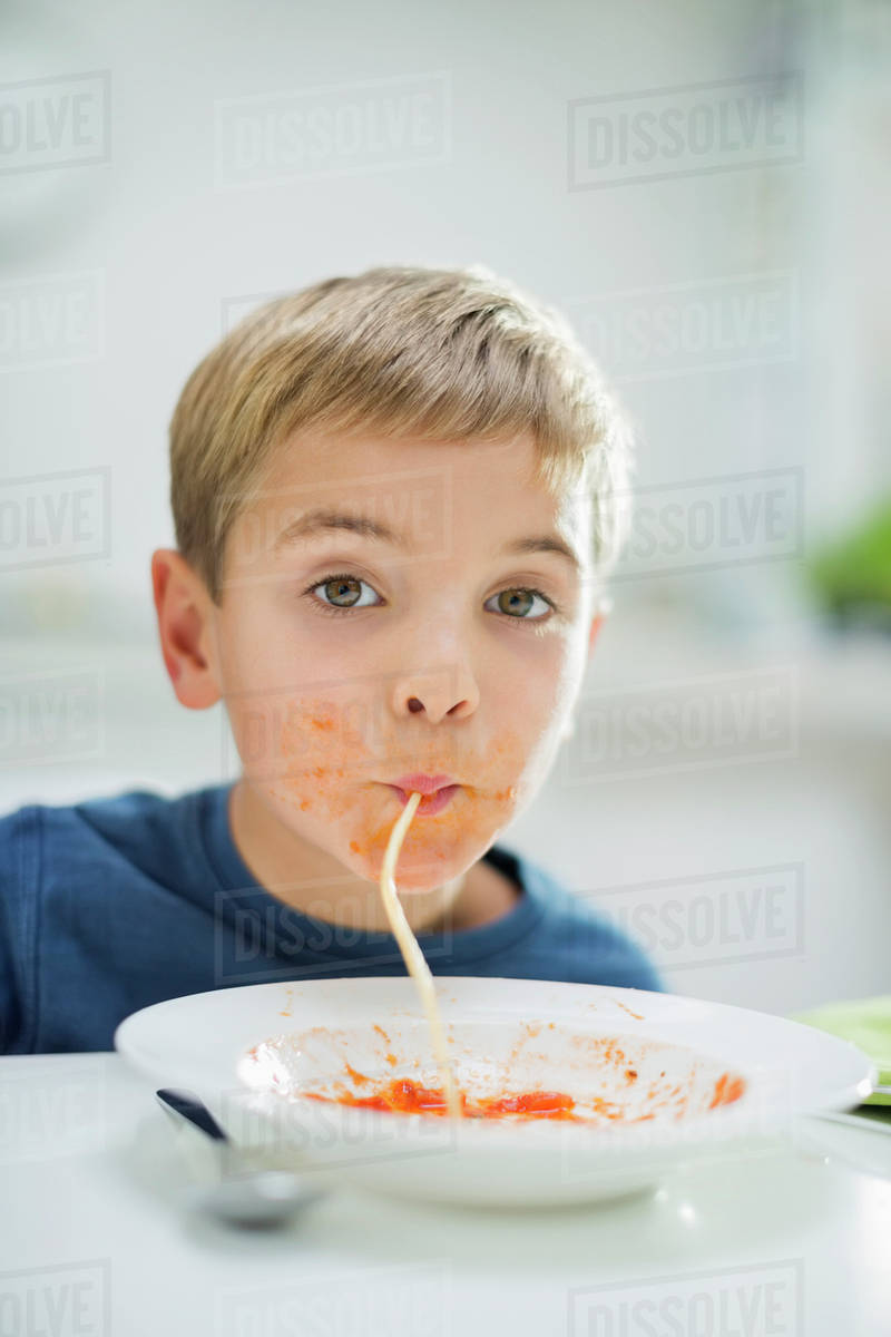 Boy slurping spaghetti at table - Stock Photo - Dissolve