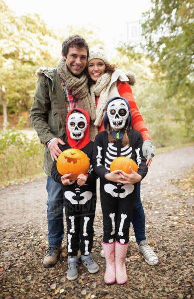 Parents smiling with children in skeleton costumes - Stock Photo - Dissolve