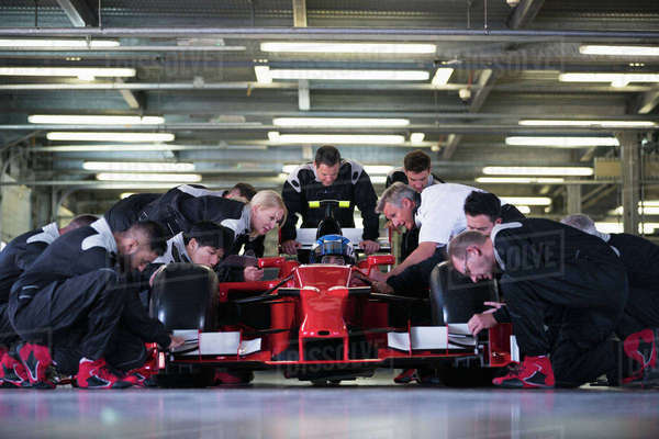 Pit crew preparing formula one race car and driver in repair garage ...