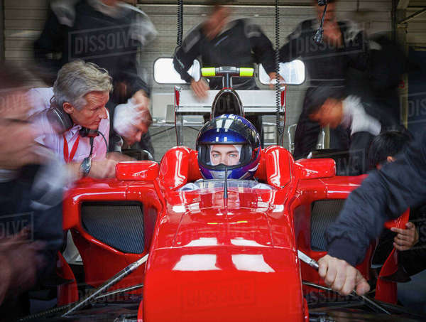 Pit crew working around serious formula one race car driver - Royalty ...