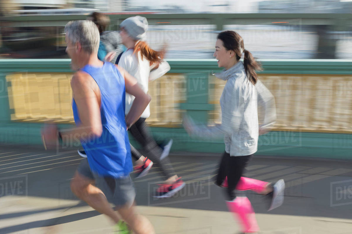 Runners running on sunny urban bridge sidewalk - Royalty-free Stock ...
