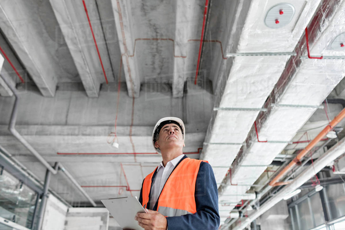 Foreman with clipboard looking up at construction site - Stock Photo ...