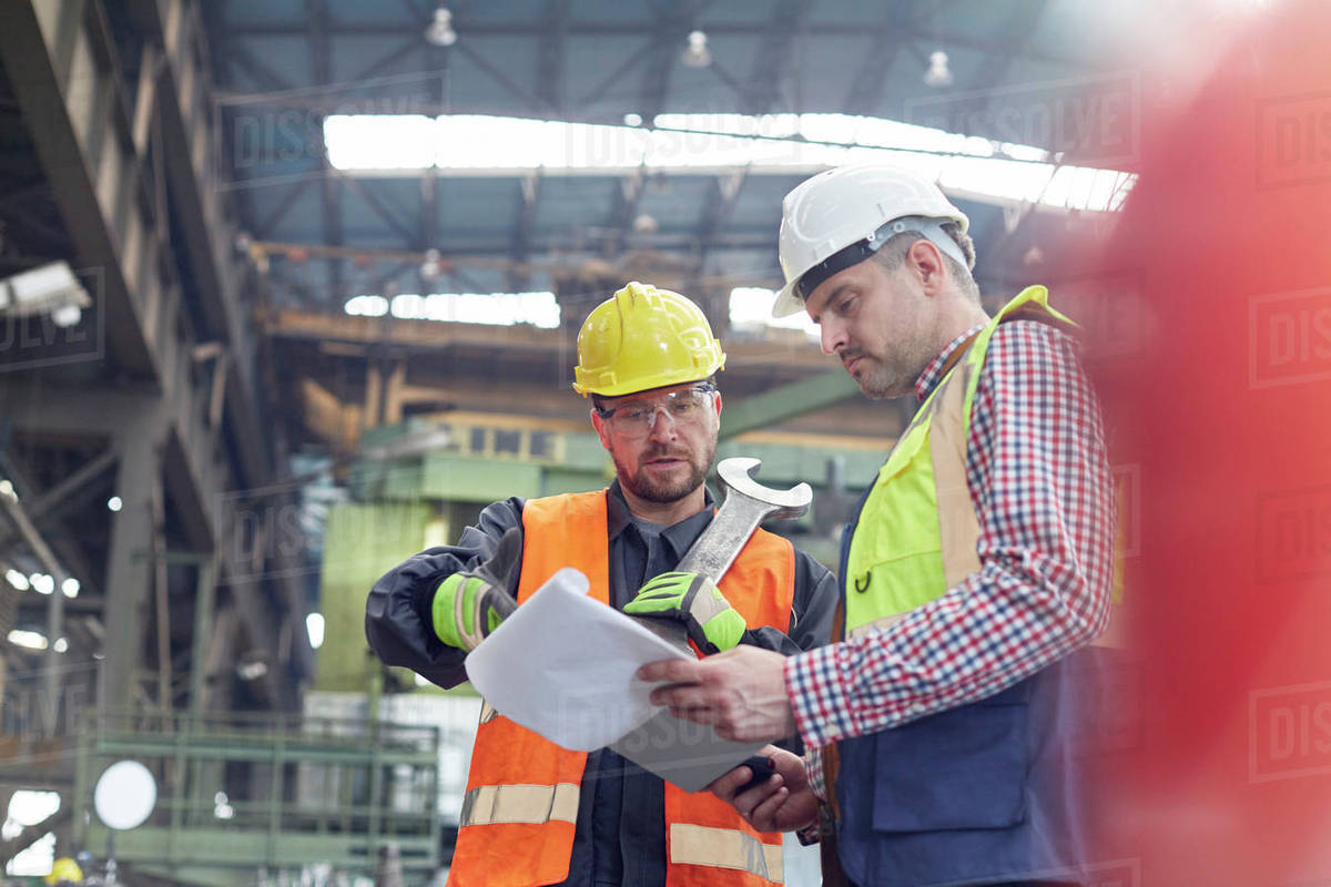 Male foreman and worker with clipboard talking in factory - Royalty ...
