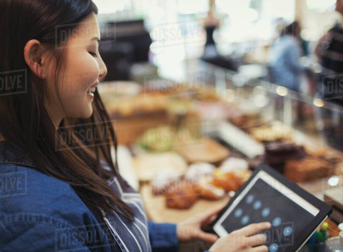 Smiling cashier using touch screen cash register in cafe - Stock Photo ...
