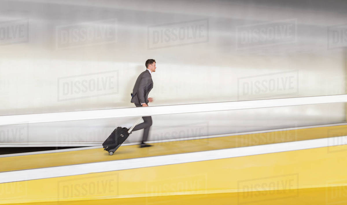Businessman running, pulling suitcase up airport ramp - Royalty-free ...