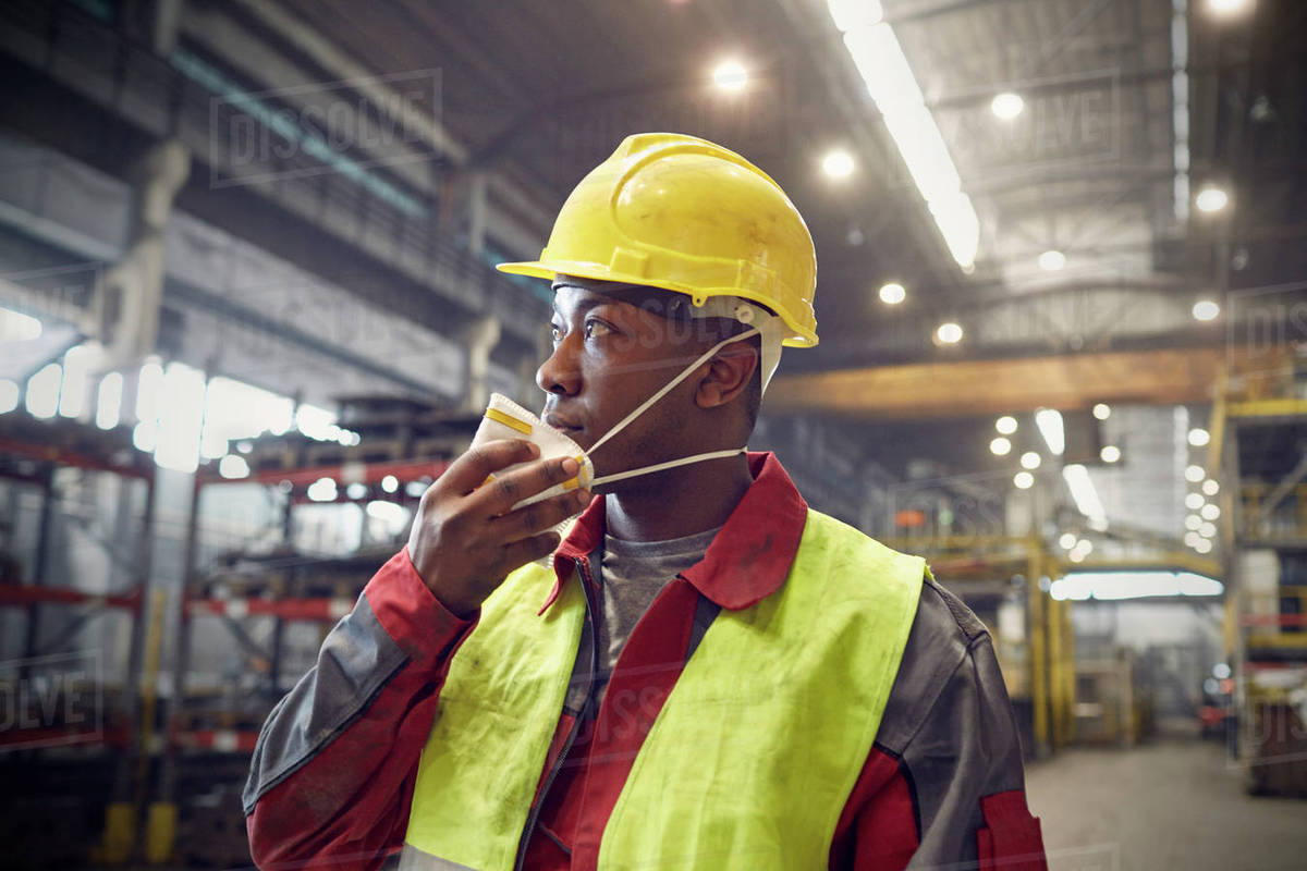 Steelworker removing protective mask in steel mill - Stock Photo - Dissolve