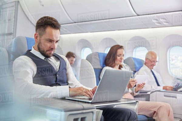 Businessman working at laptop on airplane - Royalty-free Stock Photo ...