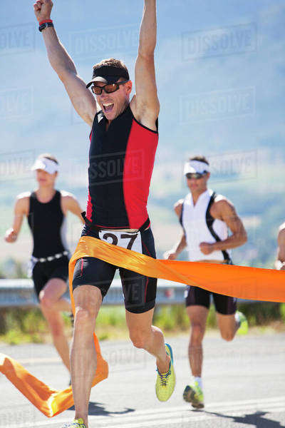 Runner crossing race finish line - Stock Photo - Dissolve