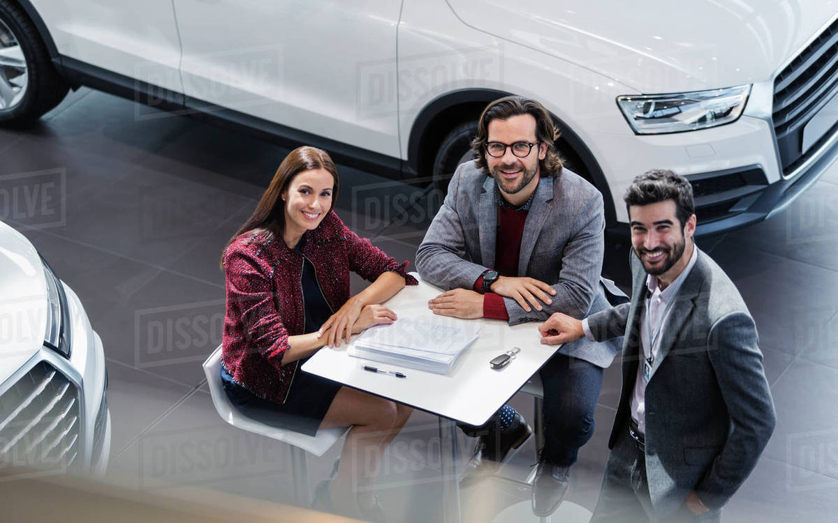 Portrait smiling car sales people meeting in car dealership showroom ...