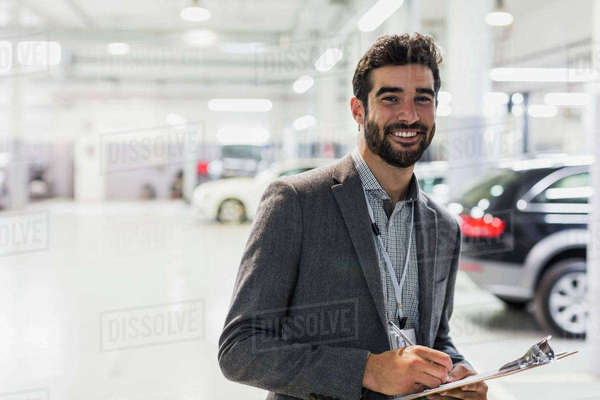 Portrait smiling, confident car salesman with clipboard in car ...
