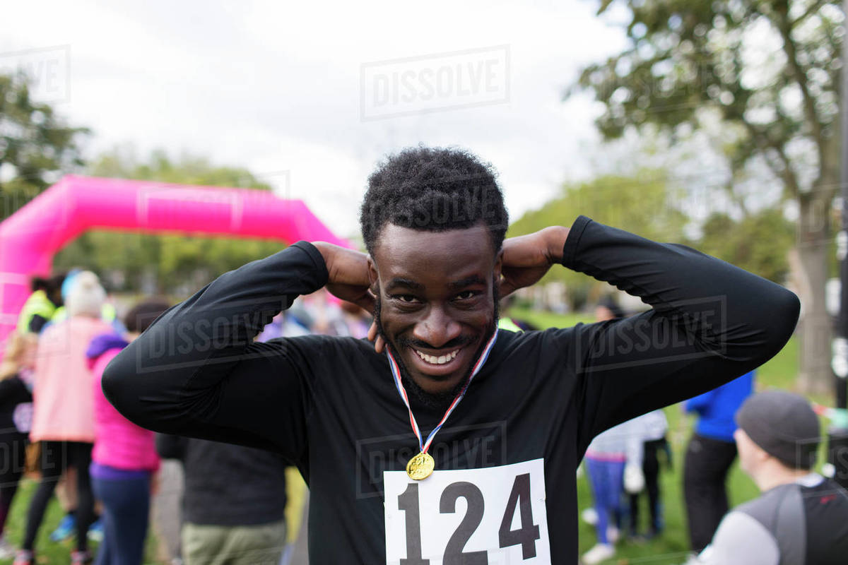 Portrait smiling, confident male runner wearing medal at charity run in ...