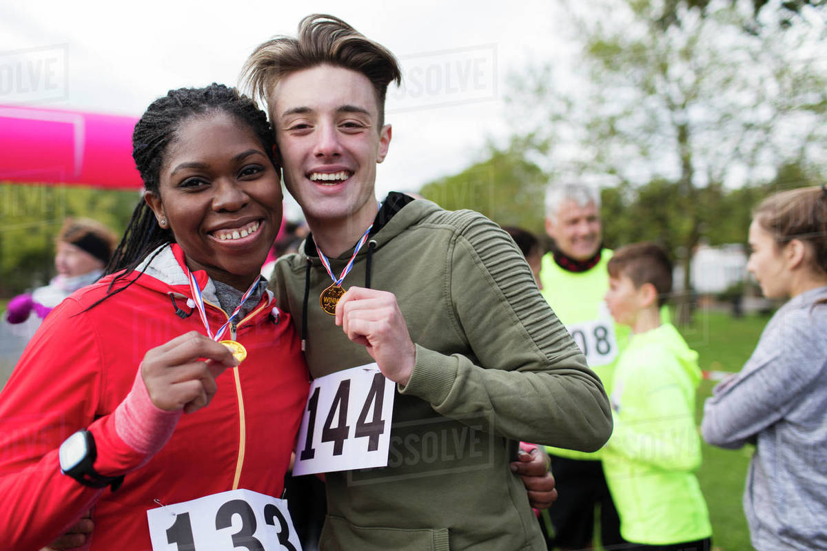 Portrait smiling, confident couple runners showing medals at charity ...