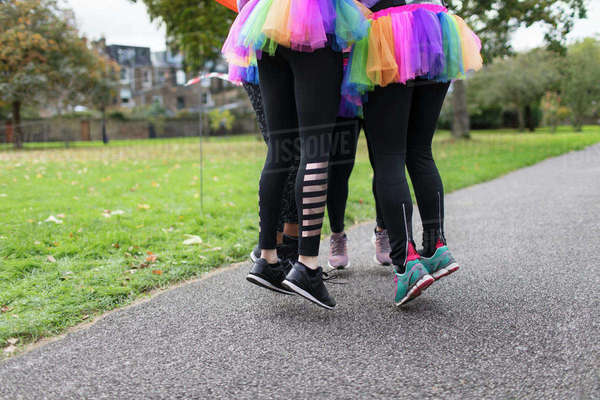 Enthusiastic female runners in tutus jumping on park path - Royalty ...